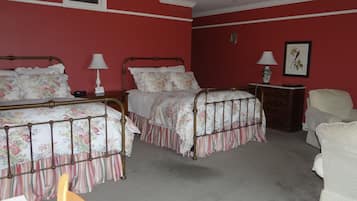 Quarto com duas camas, uma cadeira, cômoda e mesa de cabeceira.