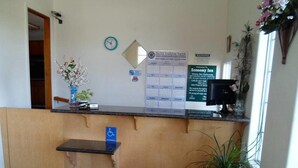 Uma receção de hotel com um relógio, um diretório e um sinal de boas-vindas.