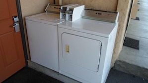 Uma área de lavanderia compacta, com máquina de lavar e secar, um armário pequeno e uma porta.