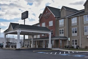 Edifício do Country Inn & Suites by Radisson com área de estacionamento coberta e placa indicando vaga para pessoas com deficiência.