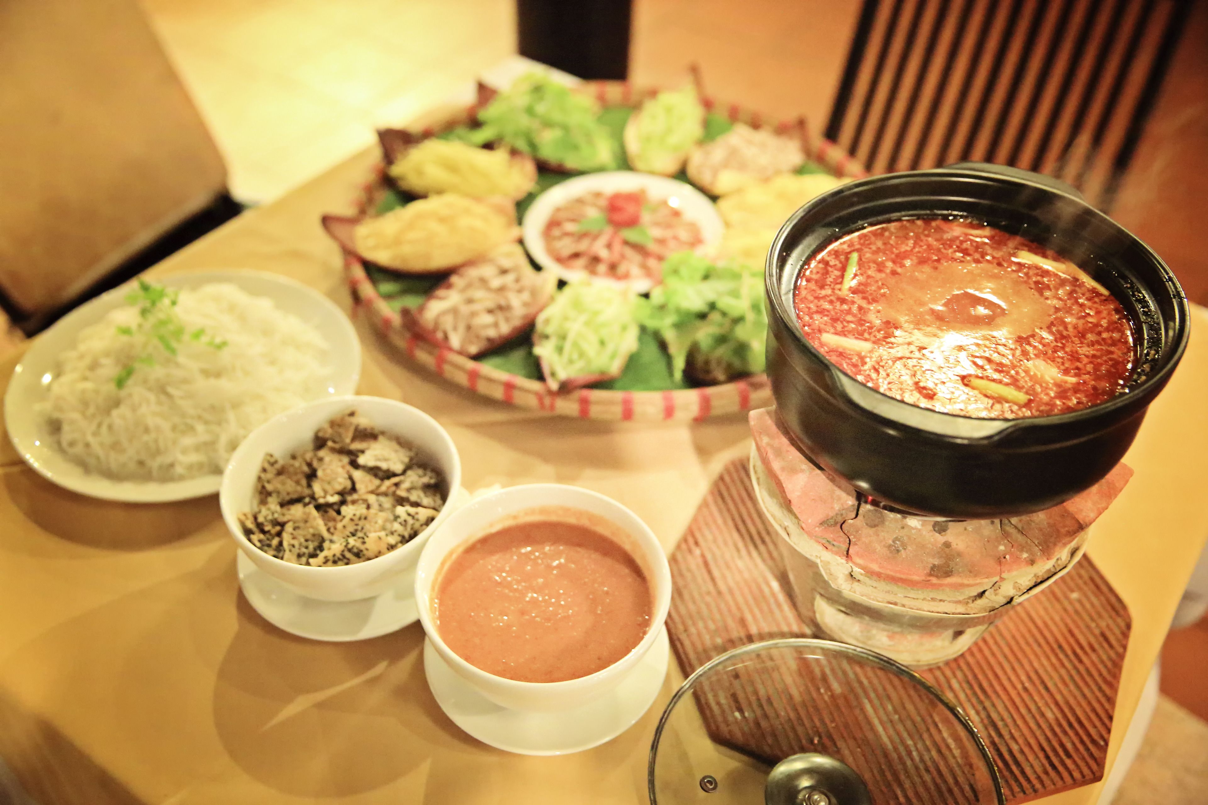 Uma mesa com diversos pratos, incluindo arroz, sopa e um pote quente.