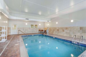Uma piscina interior com água cristalina, paredes azulejadas e área com bancos.