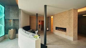 Um lobby moderno com uma recepção em curva, lareira e um pilar de pedra.