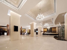 Um hall amplo com balcão de recepção, lustres e design moderno.