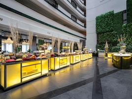 Um hall amplo com várias estações de buffet, um jardim vertical e um design de interiores moderno.
