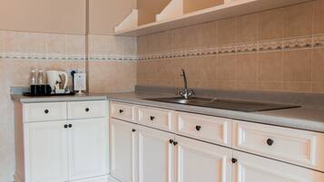 Cozinha com armários brancos, pia de aço inoxidável e backsplash decorativo.