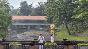 Uma ponte sobre um rio, com vegetação e uma construção tradicional.