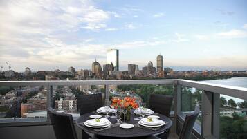 Mesa de jantar posta para seis pessoas com vista para a cidade, rodeada por cadeiras de vime.