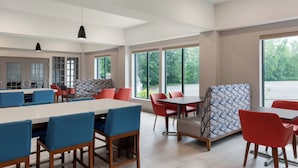 Uma sala de jantar moderna com mesas e cadeiras altas, janelas amplas e iluminação pendente.