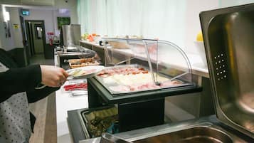 Uma área de buffet com diversas opções de comida, incluindo carnes e queijos, em um ambiente de hotel.