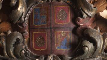 Uma detalhada escultura em madeira com quatro desenhos semelhantes a escudos, cada um com padrão e cor distintos.