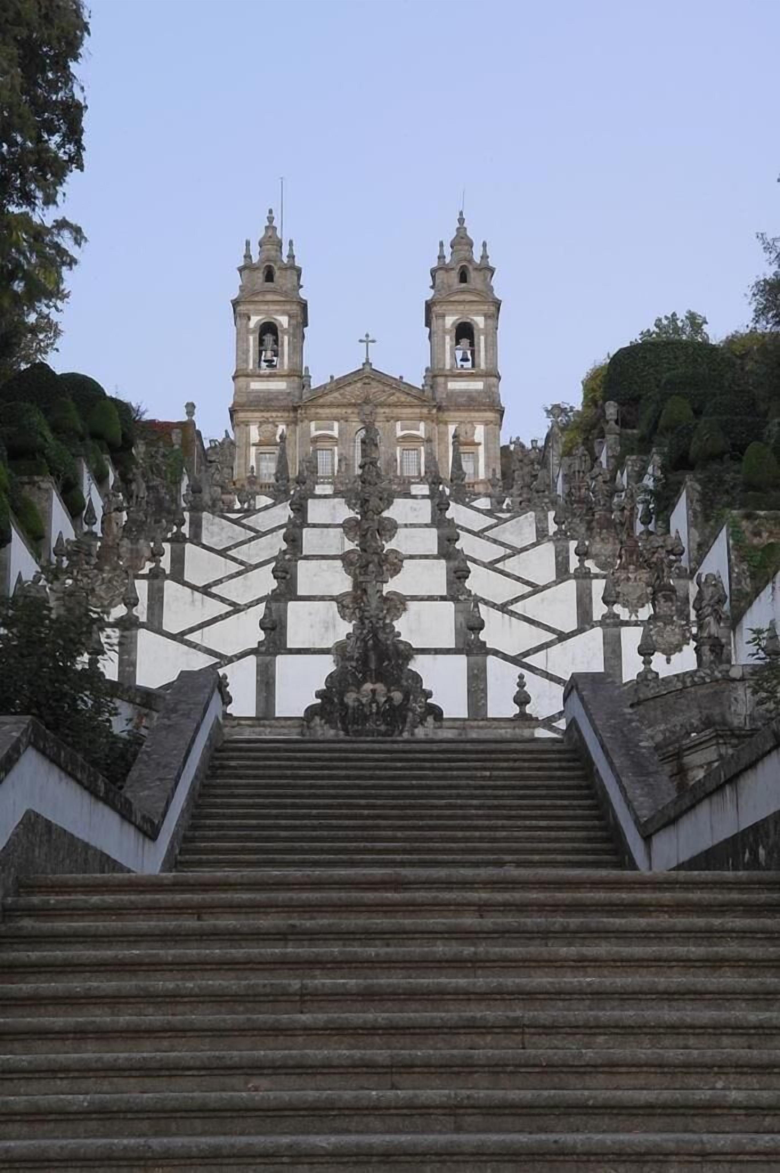 Uma escadaria imponente que leva a um edifício histórico com duas torres sineiras.