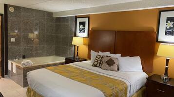 Quarto de hotel com uma cama grande, banheiro privativo com banheira e duas luminárias de cabeceira.