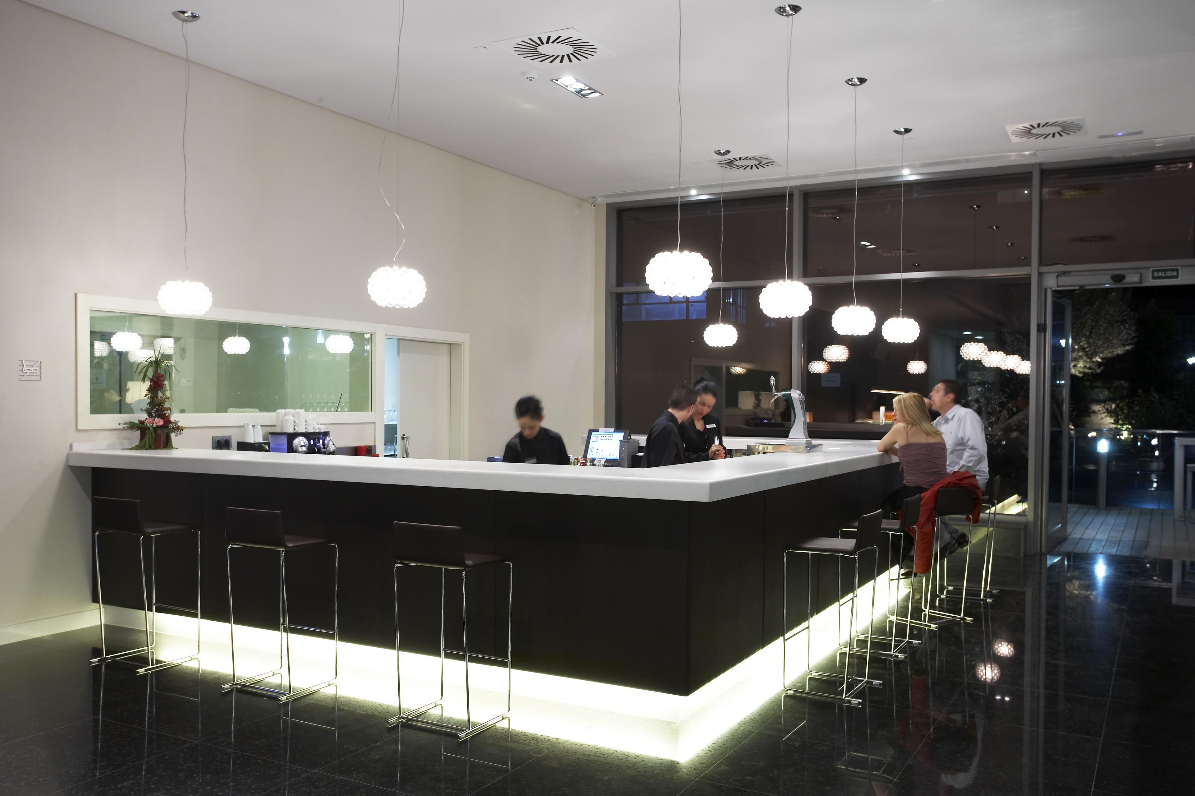 Uma área de recepção moderna com bar, assentos e uma grande janela.
