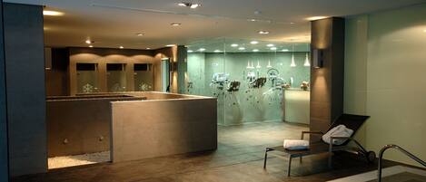 Uma área de spa moderna com uma receção, espaço para sentar e uma piscina.