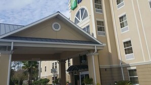 Um edifício Holiday Inn Express com fachada bege, uma placa visível e uma área de entrada coberta.