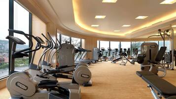 Uma academia com equipamentos de cardio, aparelhos de musculação e bancos.