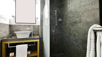 Um banheiro moderno com pia independente, chuveiro com chuveiro manual e porta-toalhas.