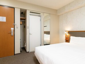 Quarto de hotel com cama, armário e banheiro.