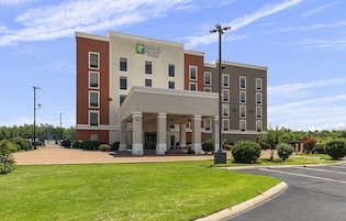 Edifício Holiday Inn Express & Suites com entrada coberta, várias janelas e estacionamento.