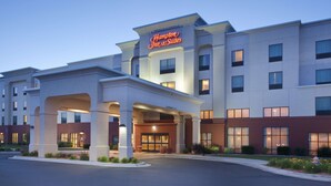 Um hotel Hampton Inn & Suites com fachada moderna, entrada ampla e janelas bem iluminadas.