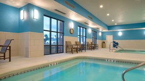 Área da piscina com espreguiçadeiras e um relógio na parede.
