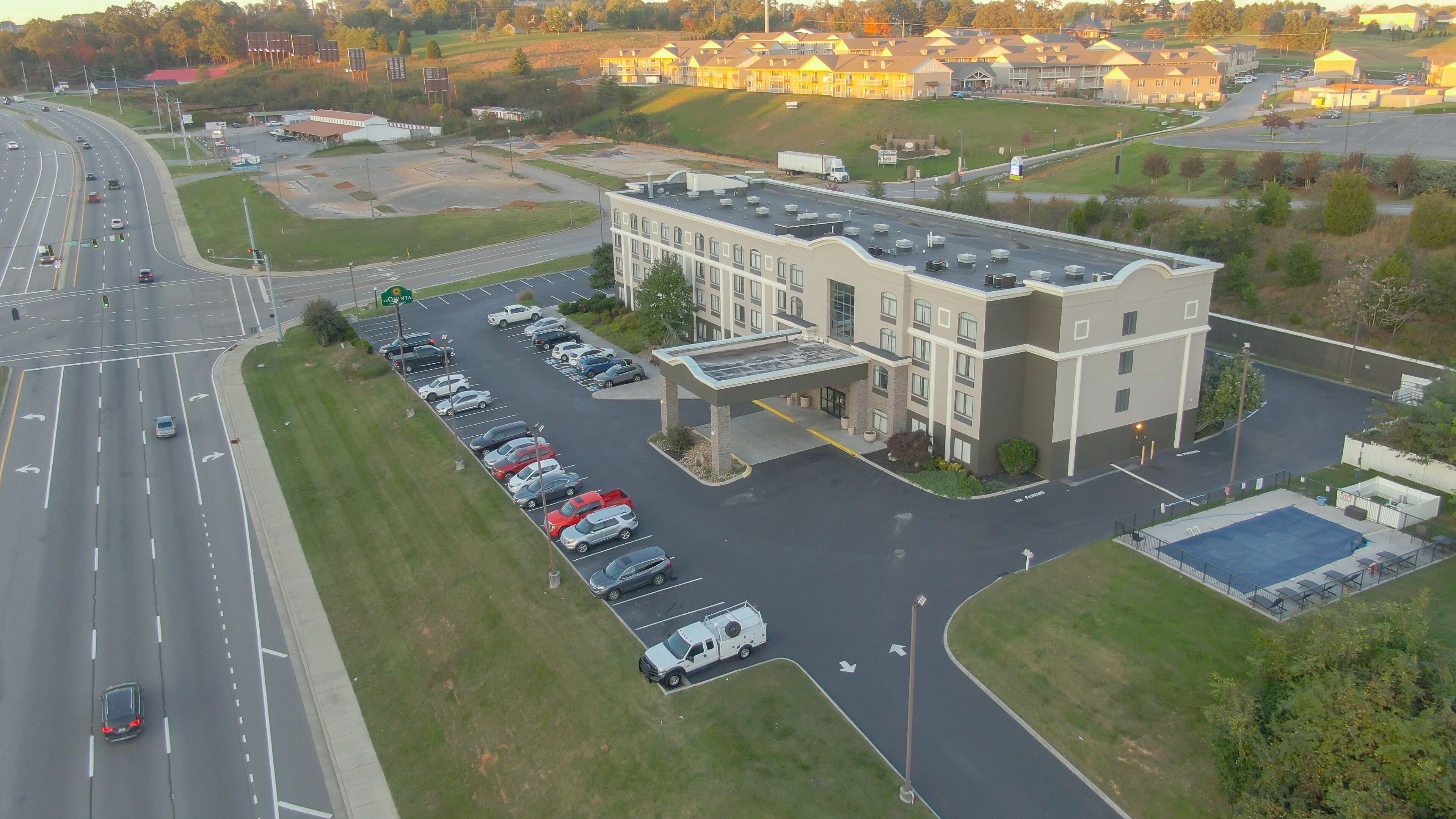 Vista aérea de um hotel com estacionamento, galeria coberta e piscina.