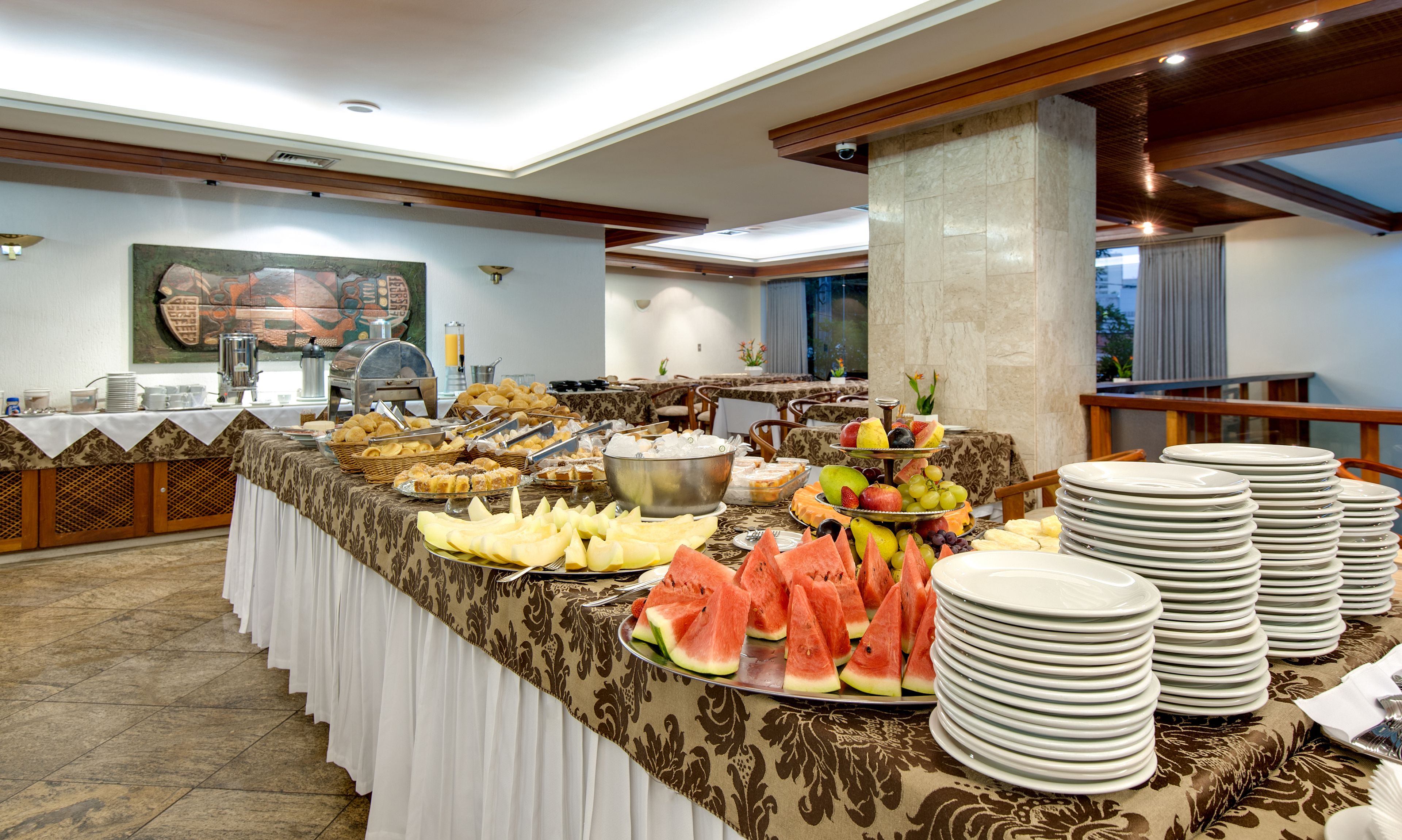 Buffet com diversas frutas, pastelaria e estação de café.