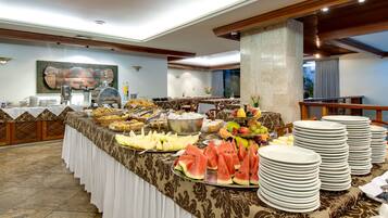Buffet com diversas frutas, pastelaria e estação de café.