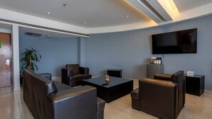 Uma área de estar moderna com sofás de couro, uma mesa de centro e uma TV de tela plana fixada na parede.