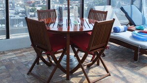 Uma área de refeições com uma mesa, cadeiras e um guarda-sol branco.