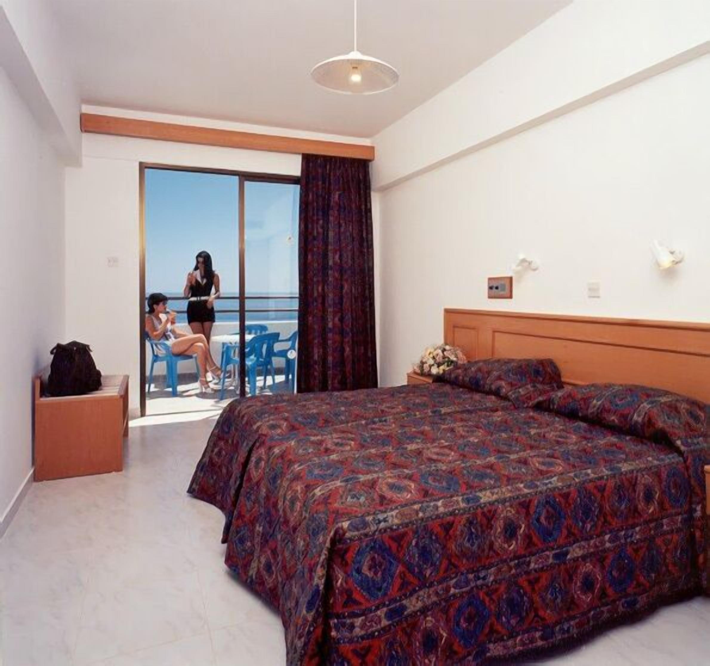 Quarto de hotel com uma cama grande, varanda e área de estar.