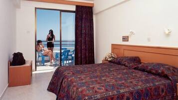 Quarto de hotel com uma cama grande, varanda e área de estar.