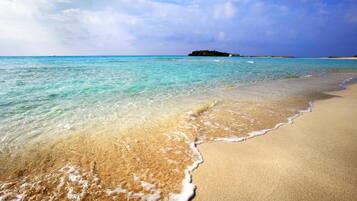 Na praia, espreguiçadeiras, guarda-sóis, toalhas de praia