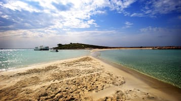 Na praia, espreguiçadeiras, guarda-sóis de praia, toalhas de praia