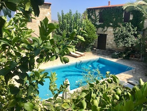 Piscina rodeada por vegetação e edifícios de pedra.