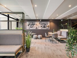 Um espaço de escritório moderno com um mural grande na parede, áreas de estar e plantas em vasos.