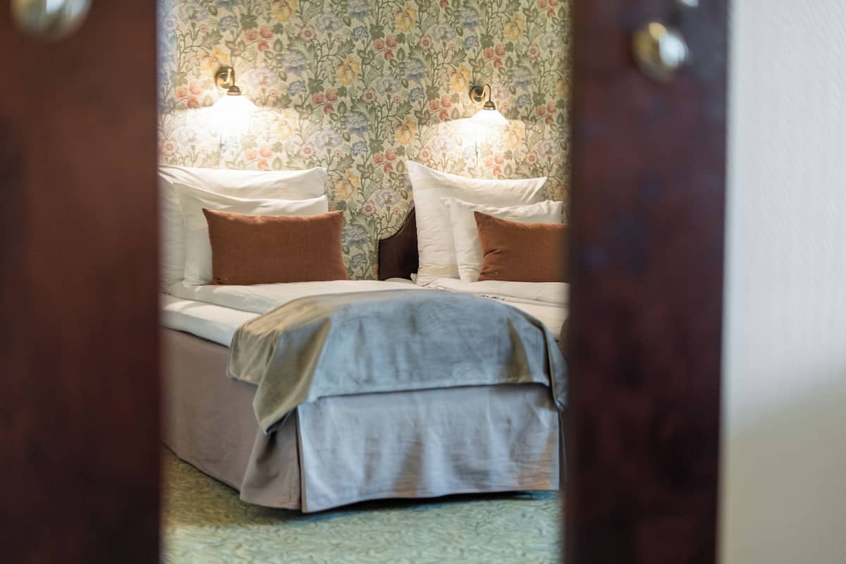 Quarto com cama, almofadas e mesa de cabeceira.