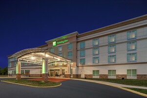 Um hotel Holiday Inn com entrada coberta, vários andares e fachada bem iluminada.