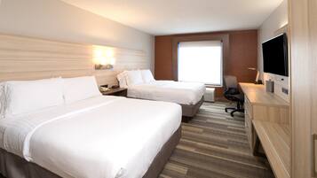 Quarto de hotel com duas camas, uma escrivaninha, uma cadeira, uma televisão e uma janela.