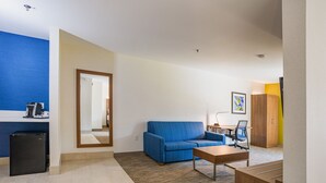 Um espaço compacto com cozinha compacta, um sofá azul, uma mesa de madeira e uma pequena escrivaninha com cadeira.