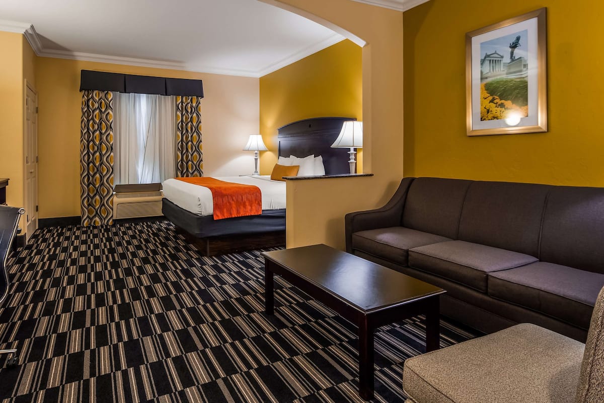 Quarto de hotel com cama, sofá, escrivaninha e cadeira.