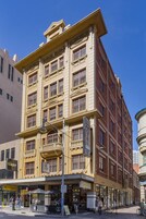 Um hotel de vários andares com design arquitetônico clássico, apresentando uma entrada imponente com toldo e placa.