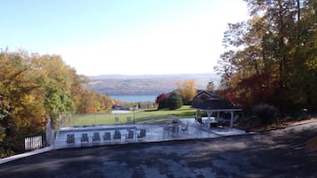 Vista de uma propriedade com um gazebo, área de estar externa e vista para um lago e colinas.