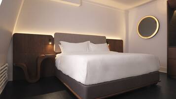 Quarto moderno com cama grande, cabeceira de madeira, mesas de cabeceira e um espelho redondo na parede.