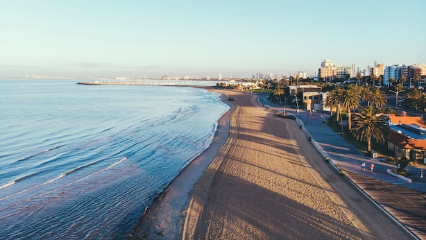 Paisagem costeira urbana com praia, calçadão e edifícios altos.