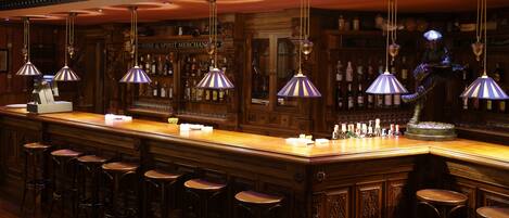 Uma área de bar com vários bancos, luminárias pendentes e uma prateleira de bebidas bem abastecida.