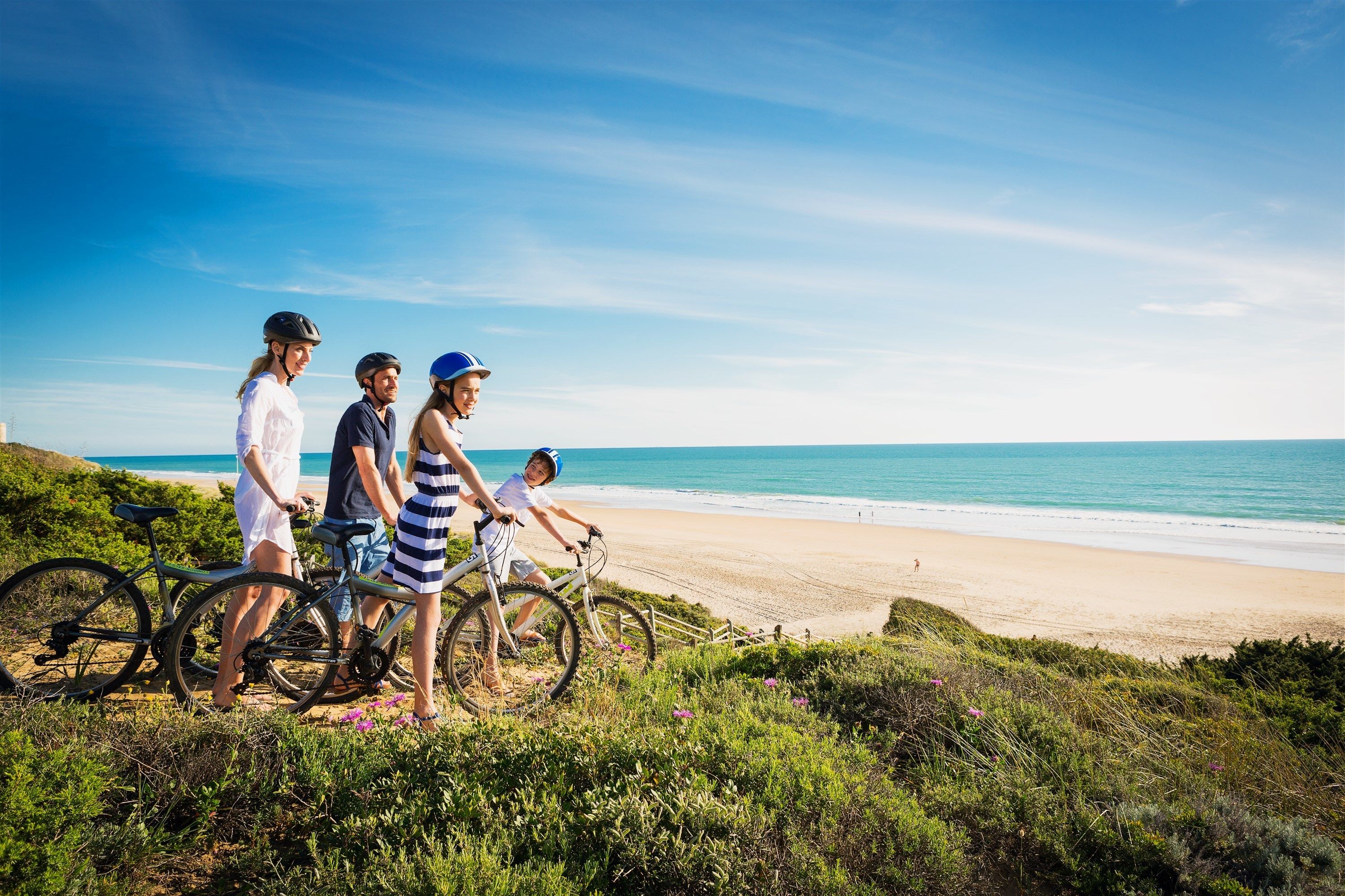 Um grupo de pessoas com bicicletas perto de uma praia.