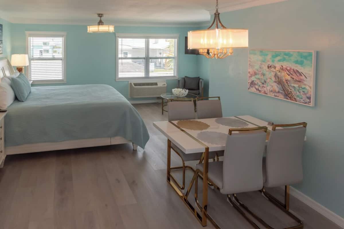 Quarto com cama, mesa de cabeceira, abajur e um quadro na parede.