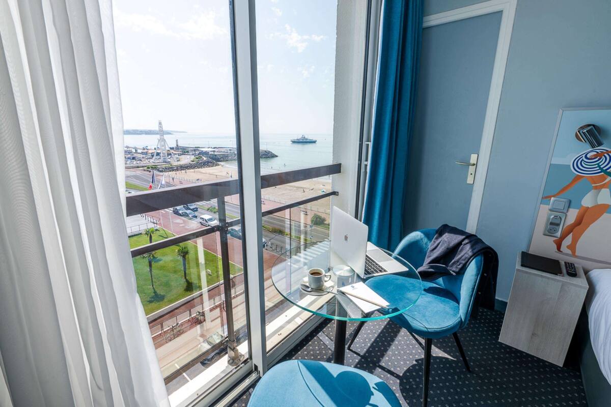 Quarto de hotel com varanda, um laptop, uma cadeira e uma cama.